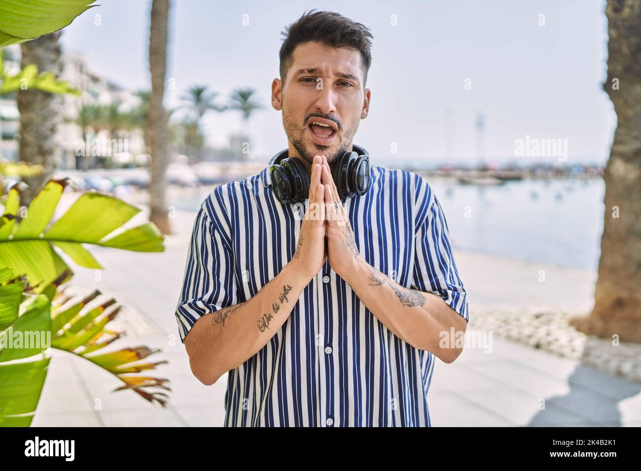 Young handsome man listening to music using headphones outdoors begging ...