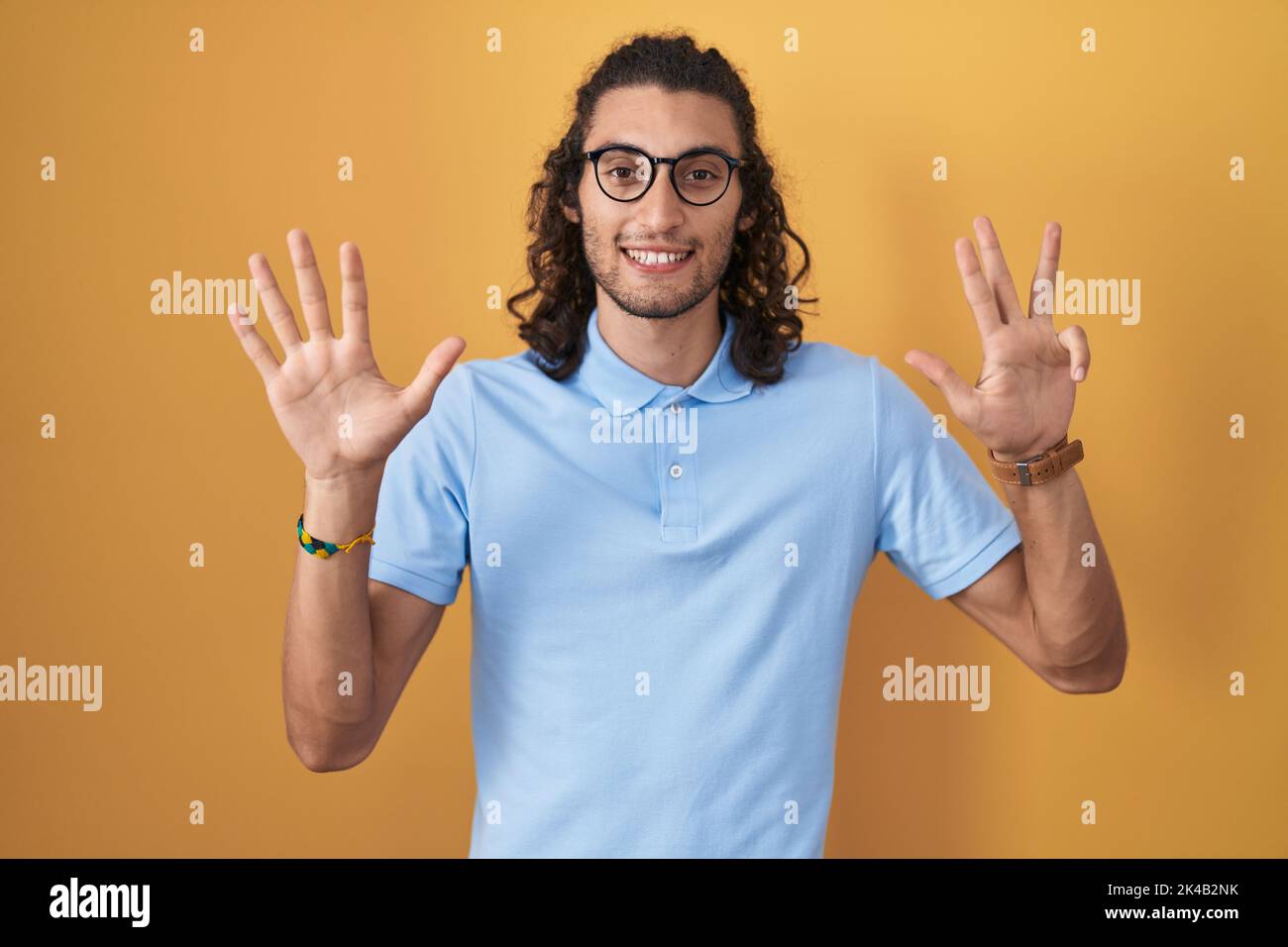 Young hispanic man standing over yellow background showing and pointing ...