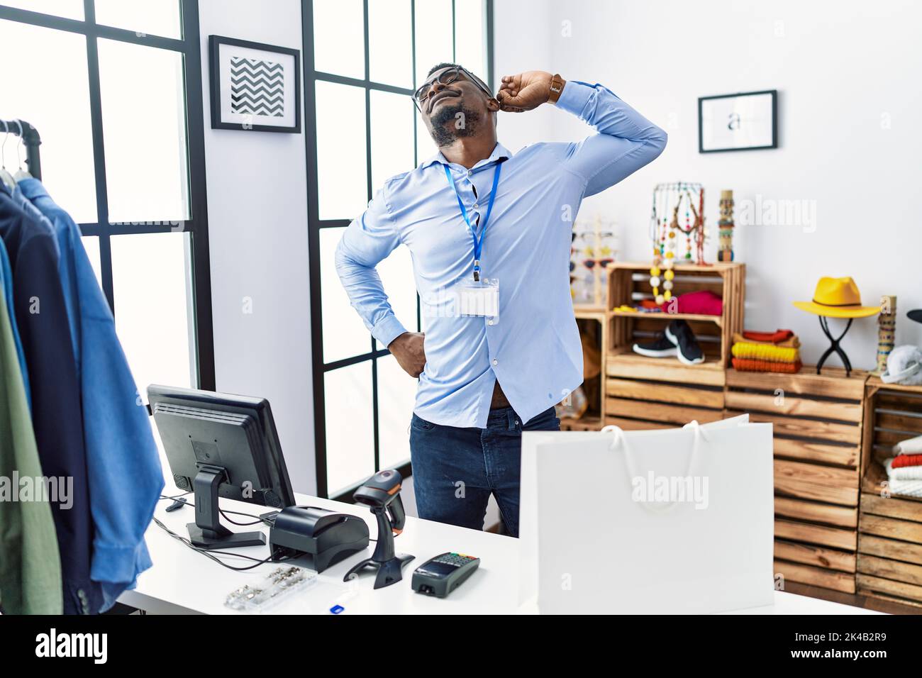 Young african man working as manager at retail boutique stretching back ...