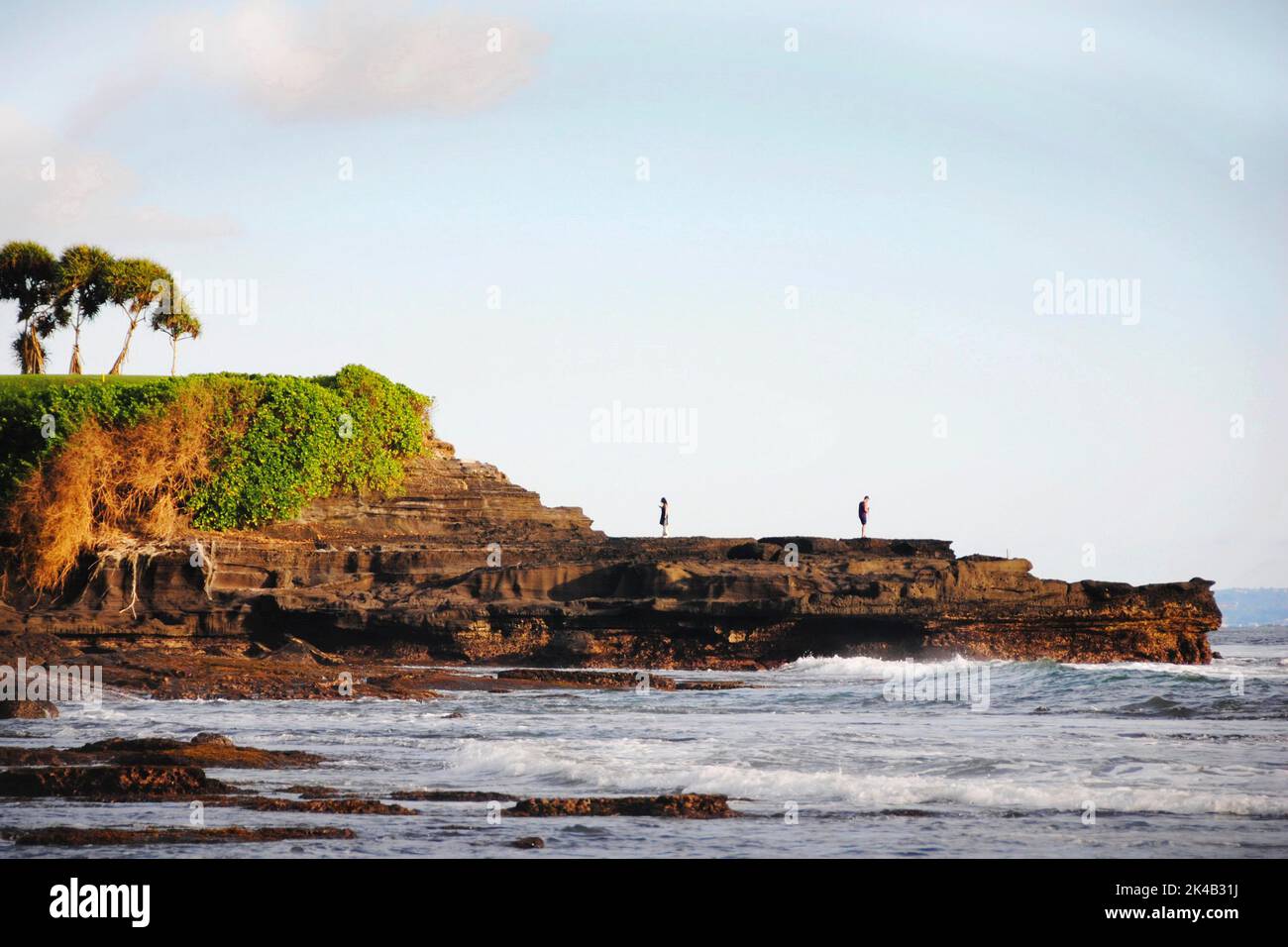 Young man and woman back to back holding mobile phones in a scenic ...