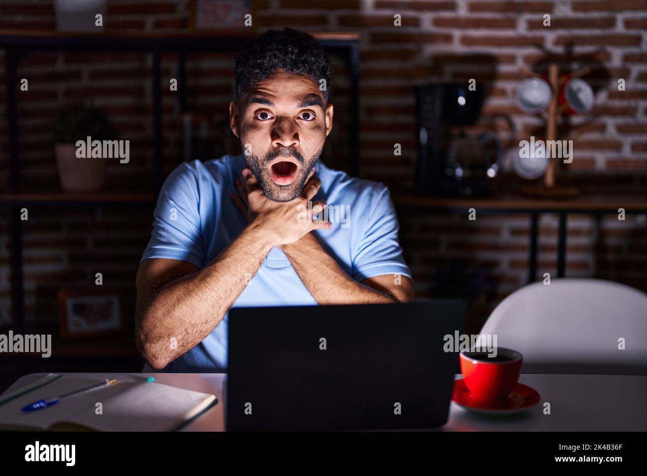 Hispanic man with beard using laptop at night shouting and suffocate ...