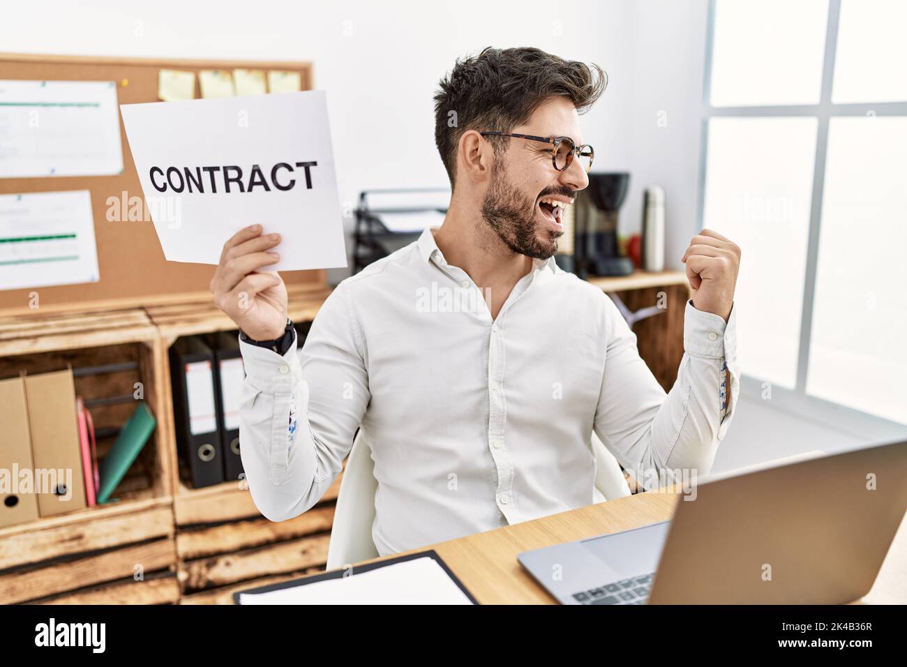 Young man with beard holding contract paper at the office pointing ...