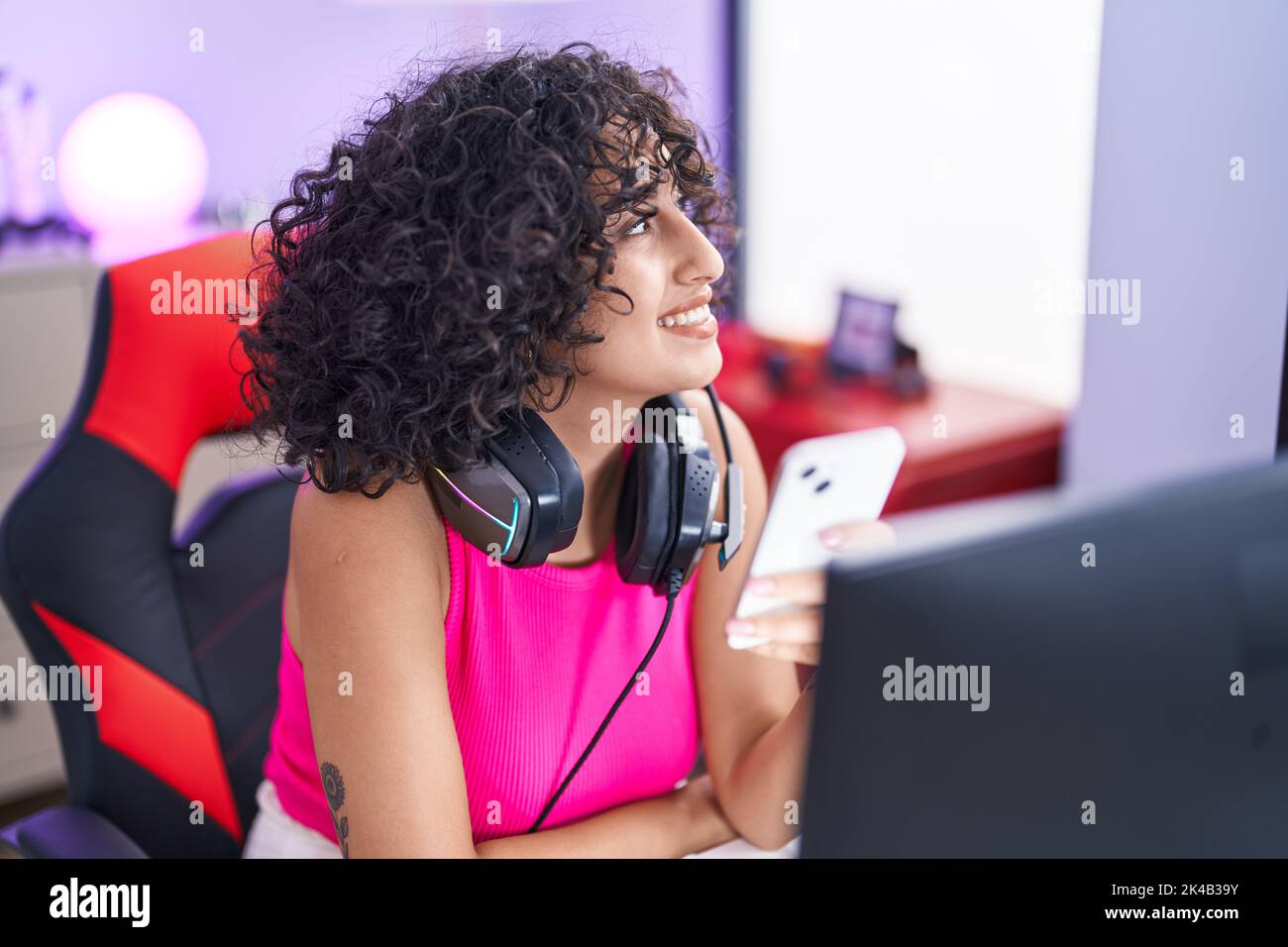 Young middle eastern woman streamer using computer and smartphone at ...