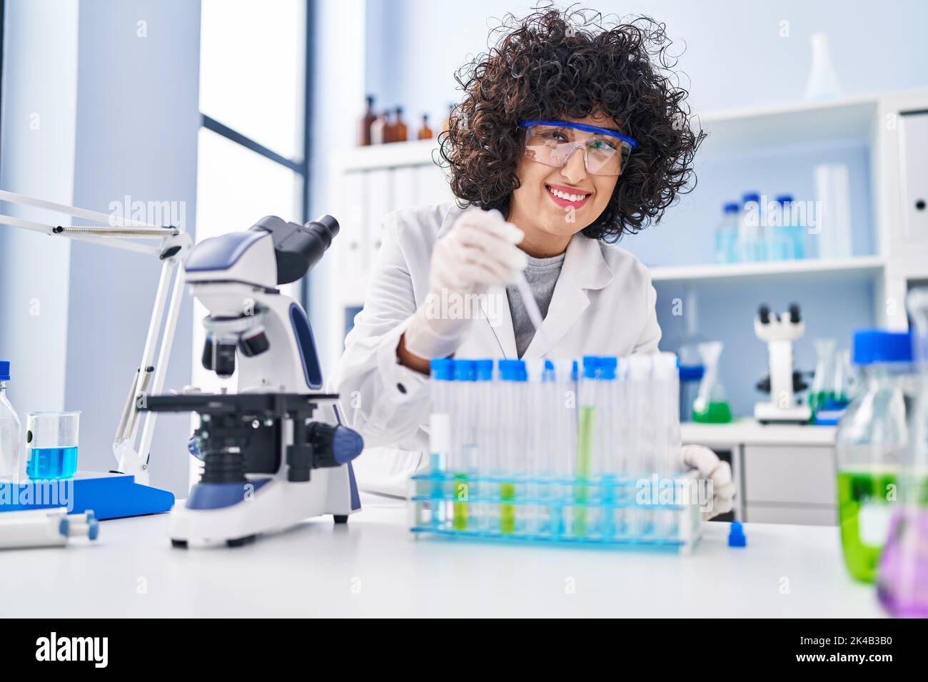 Young middle east woman scientist pouring liquid on test tubes at ...