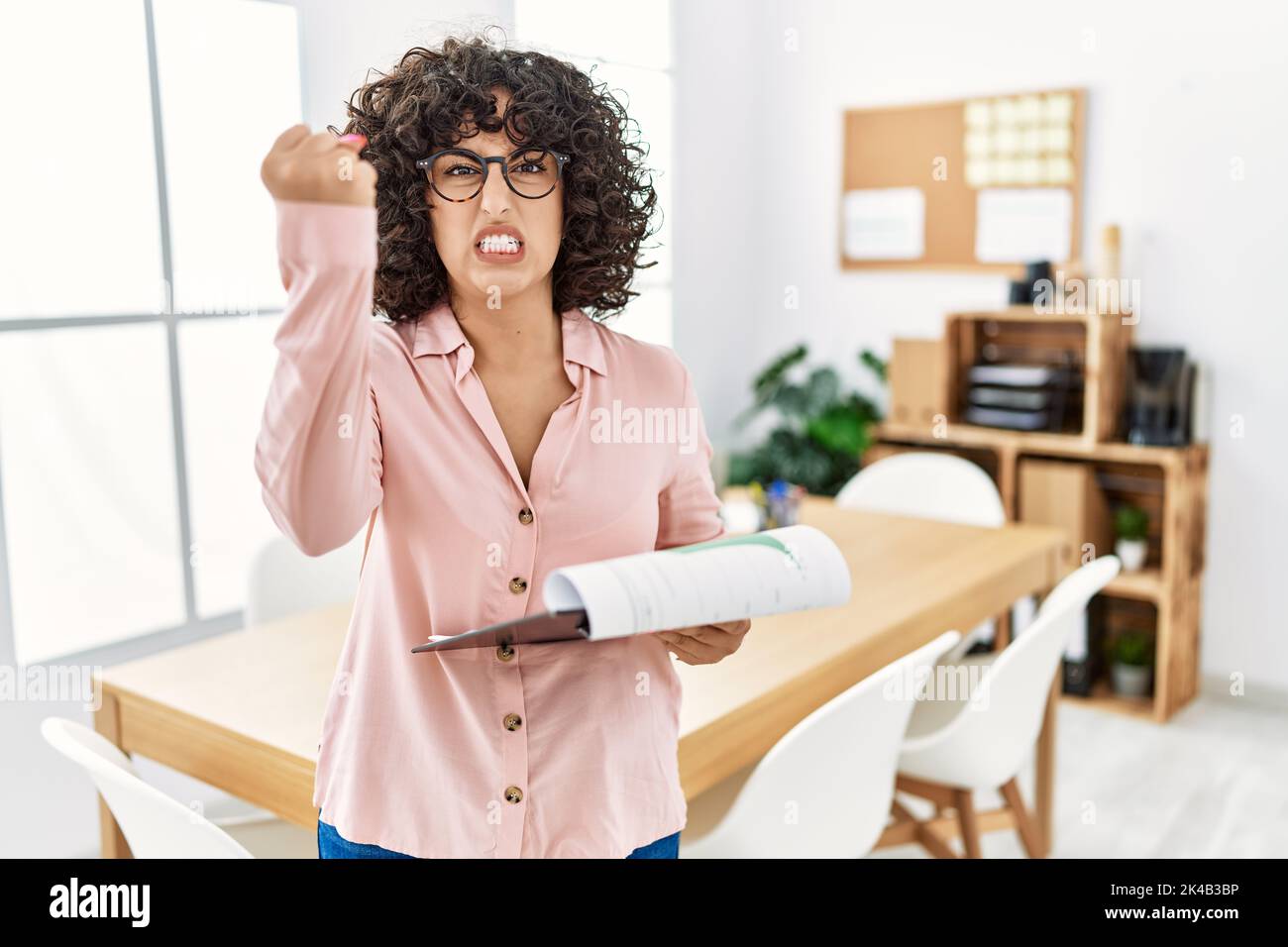 Young middle eastern woman wearing business style at office angry and ...