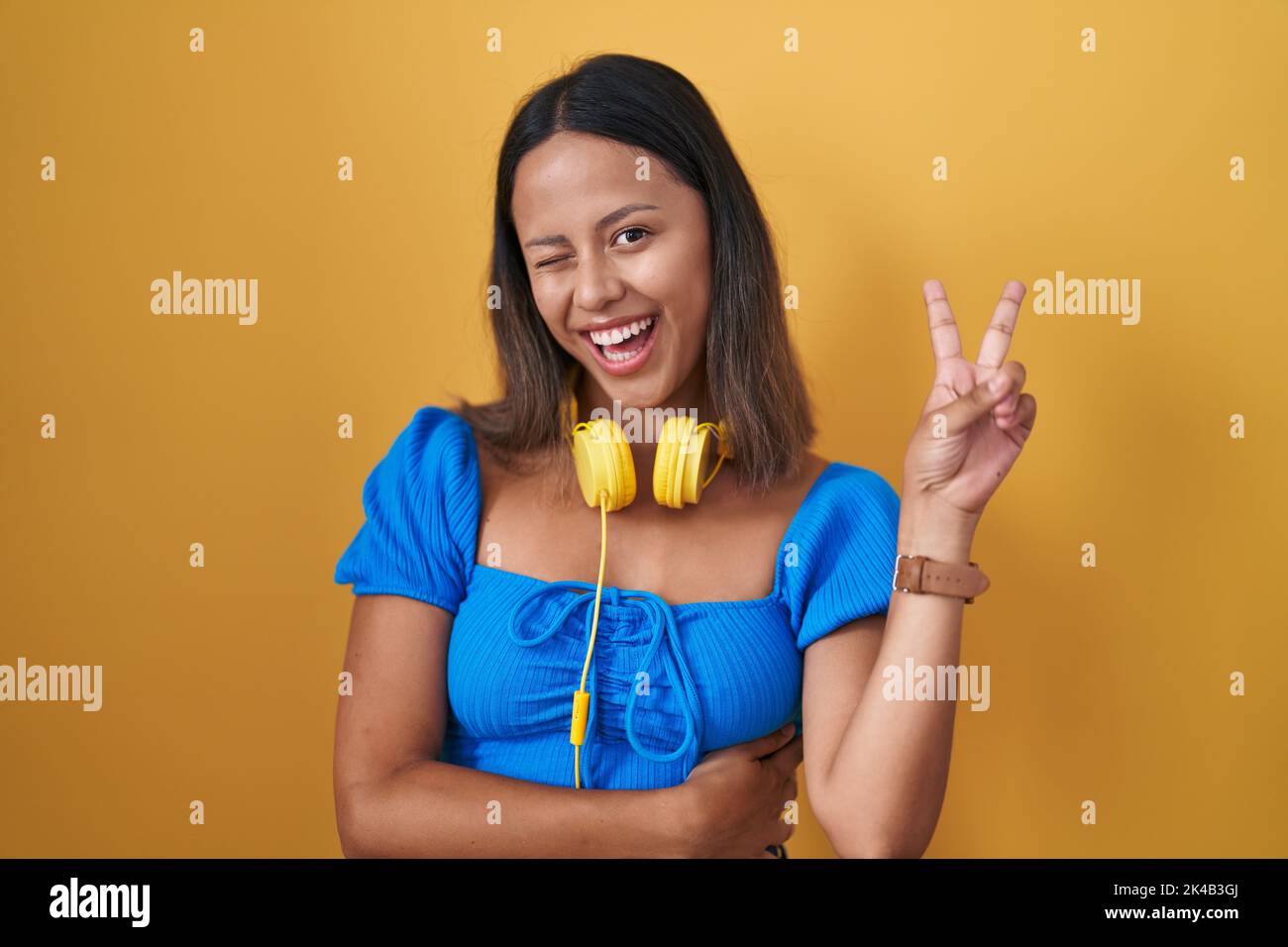 Hispanic young woman standing over yellow background smiling with happy ...