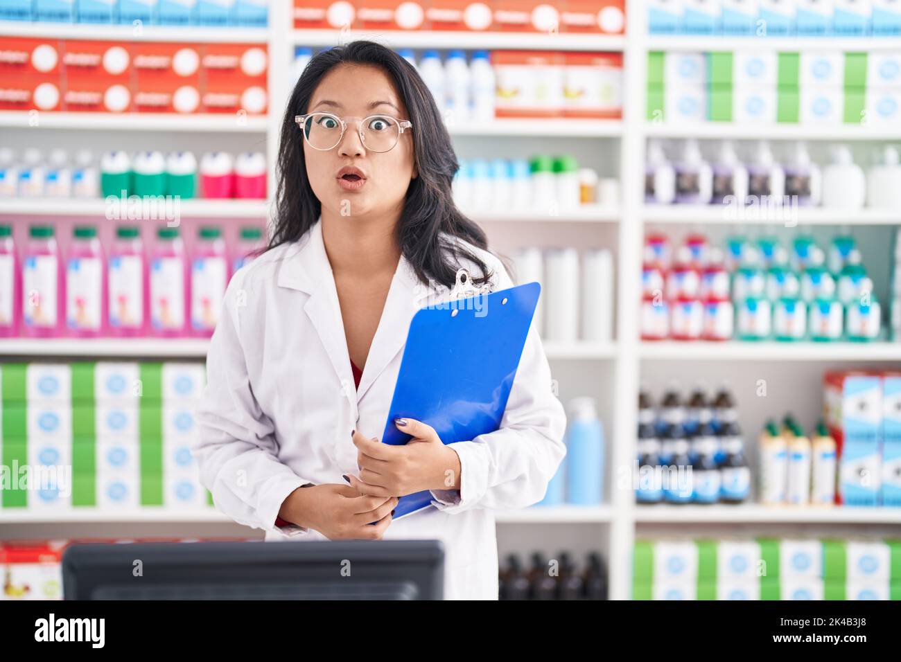 Asian young woman working at pharmacy drugstore holding clipboard ...