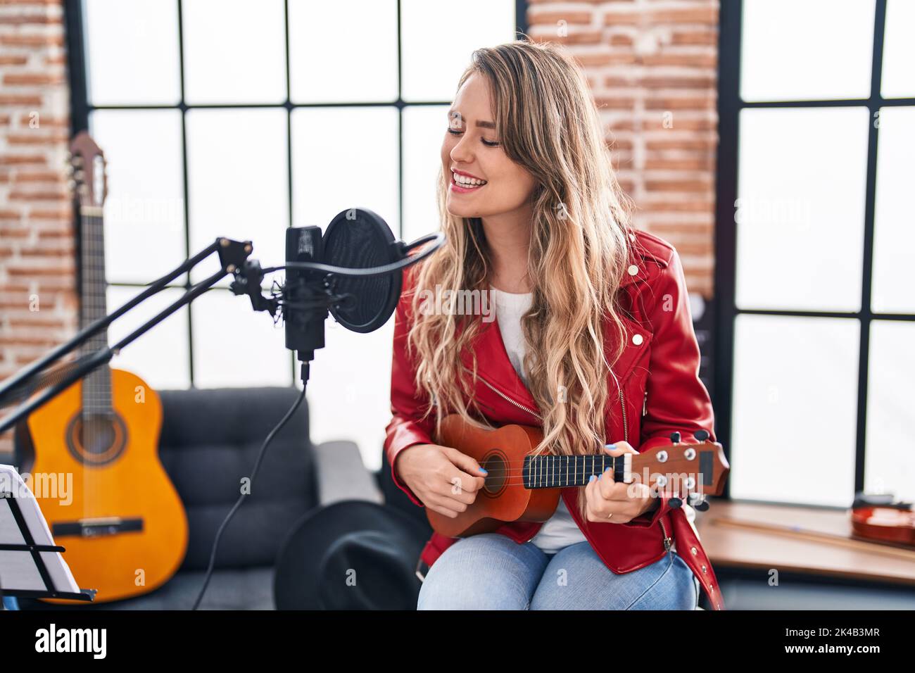 Young woman musician singing song playing ukulele at music studio Stock ...