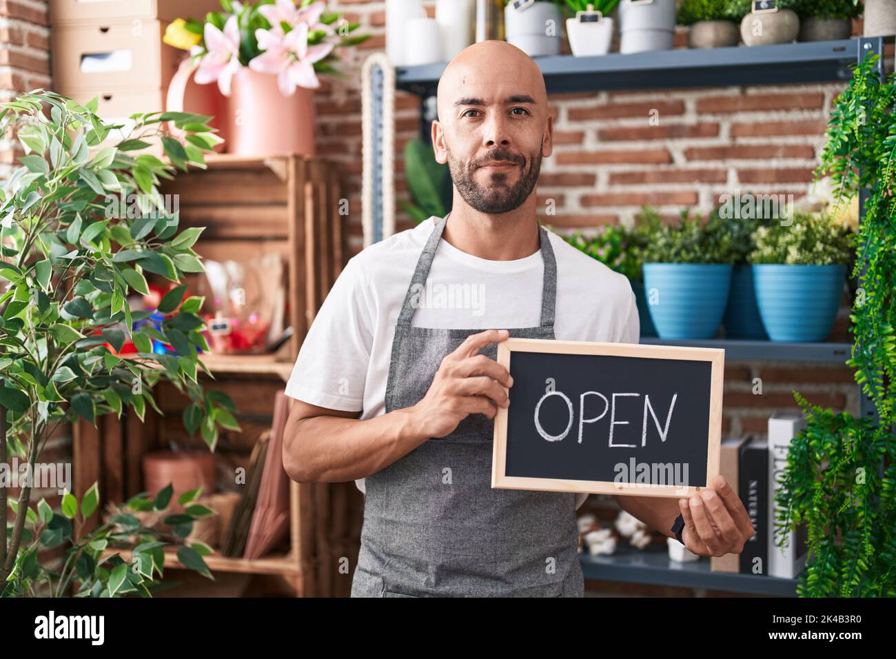 Middle age bald man working at florist holding open sign relaxed with ...