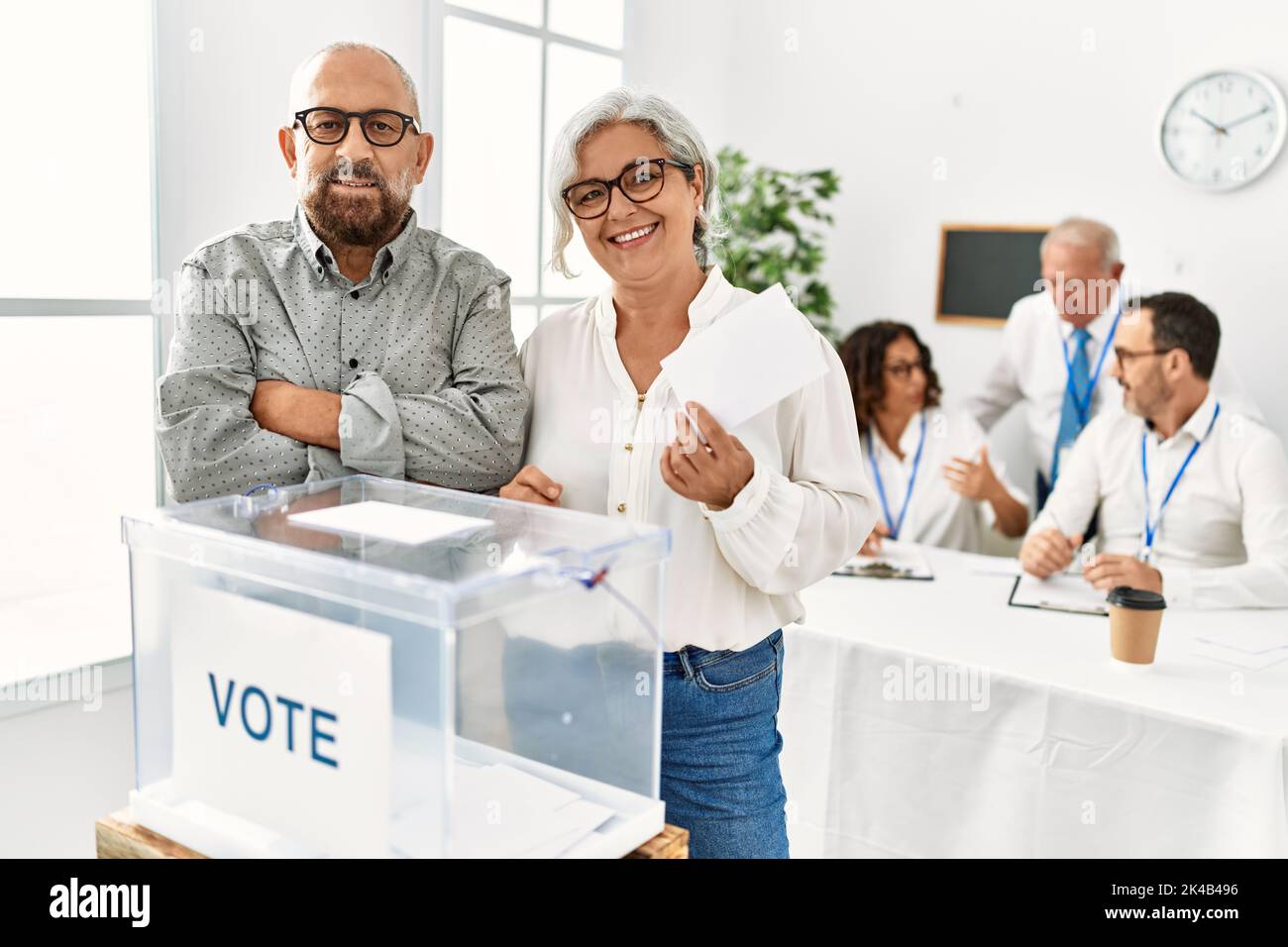 Middle age voter couple smiling happy putting vote in voting box at ...
