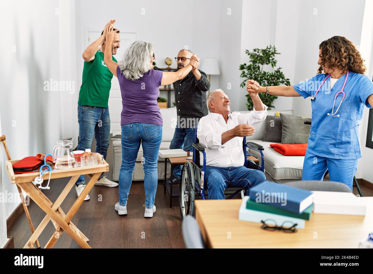Group of retired people having party dancing with doctor and volunteer ...
