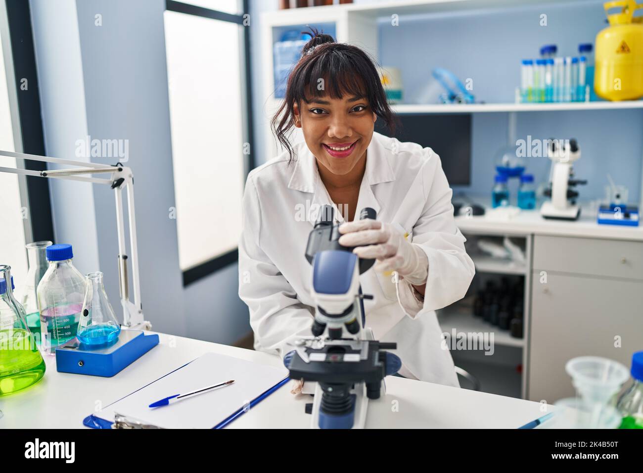 Young beautiful latin woman scientist smiling confident using ...
