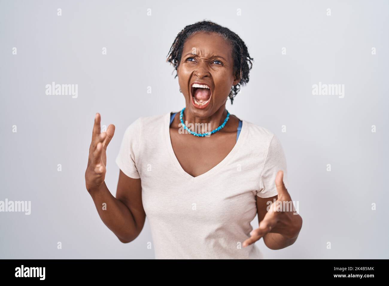 African woman with dreadlocks standing over white background crazy and ...