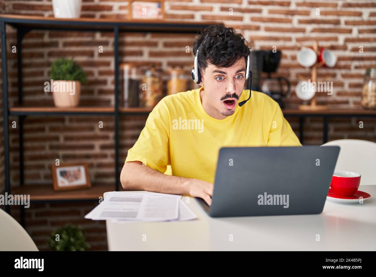 Hispanic man wearing call center agent headset working from home scared ...