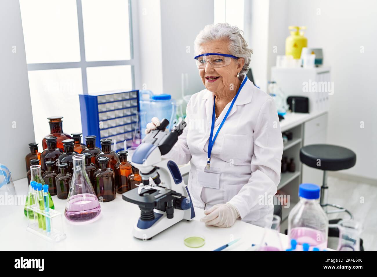 Senior woman with grey hair working at scientist laboratory looking ...
