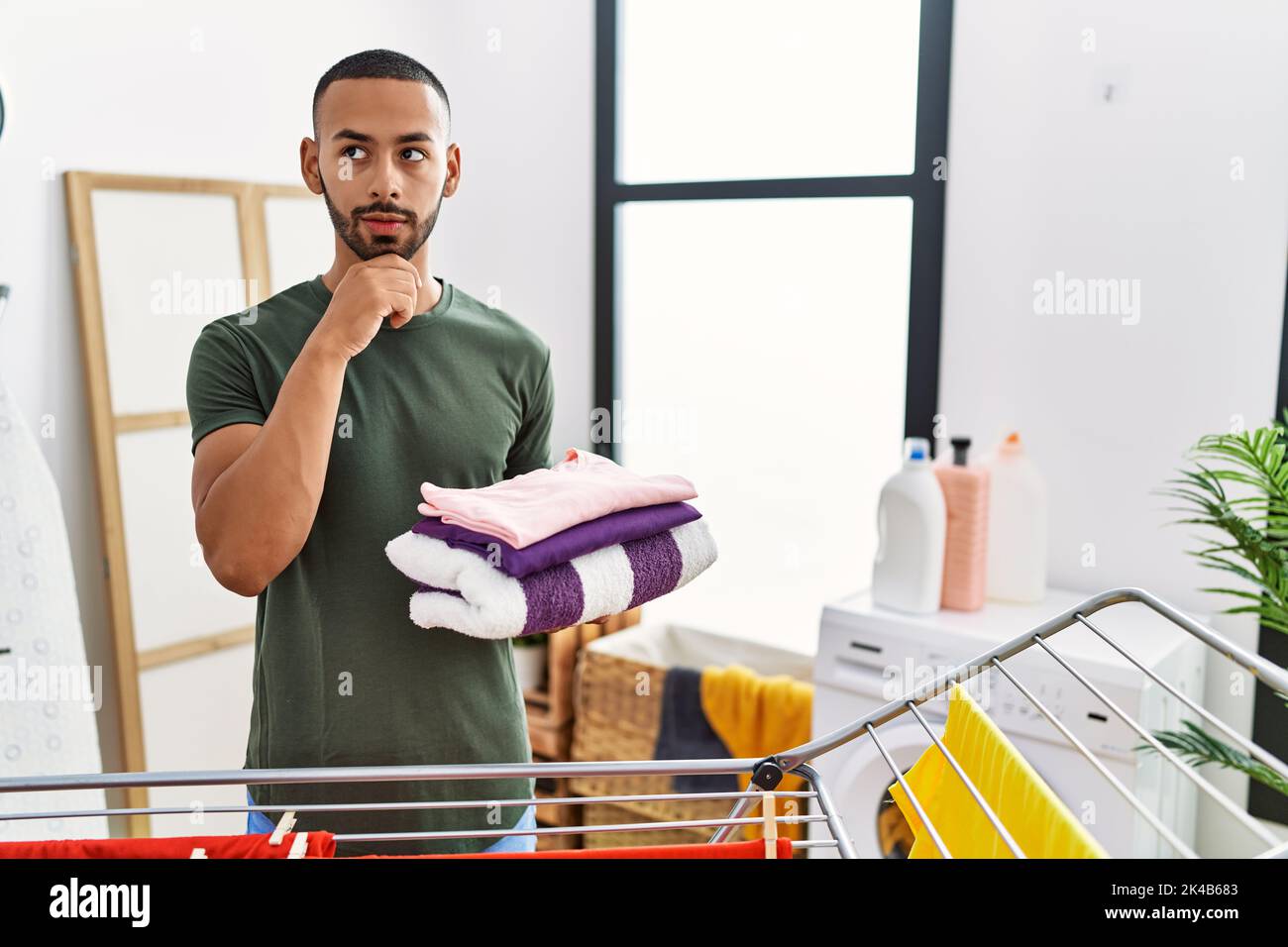 African american man holding folded laundry from clothline serious face ...