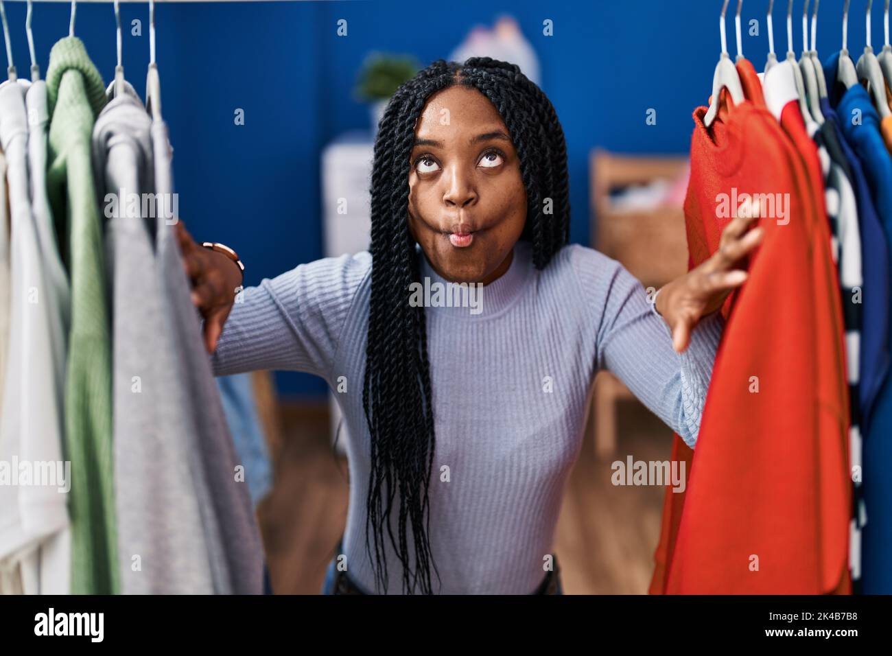African american woman searching clothes on clothing rack making fish ...
