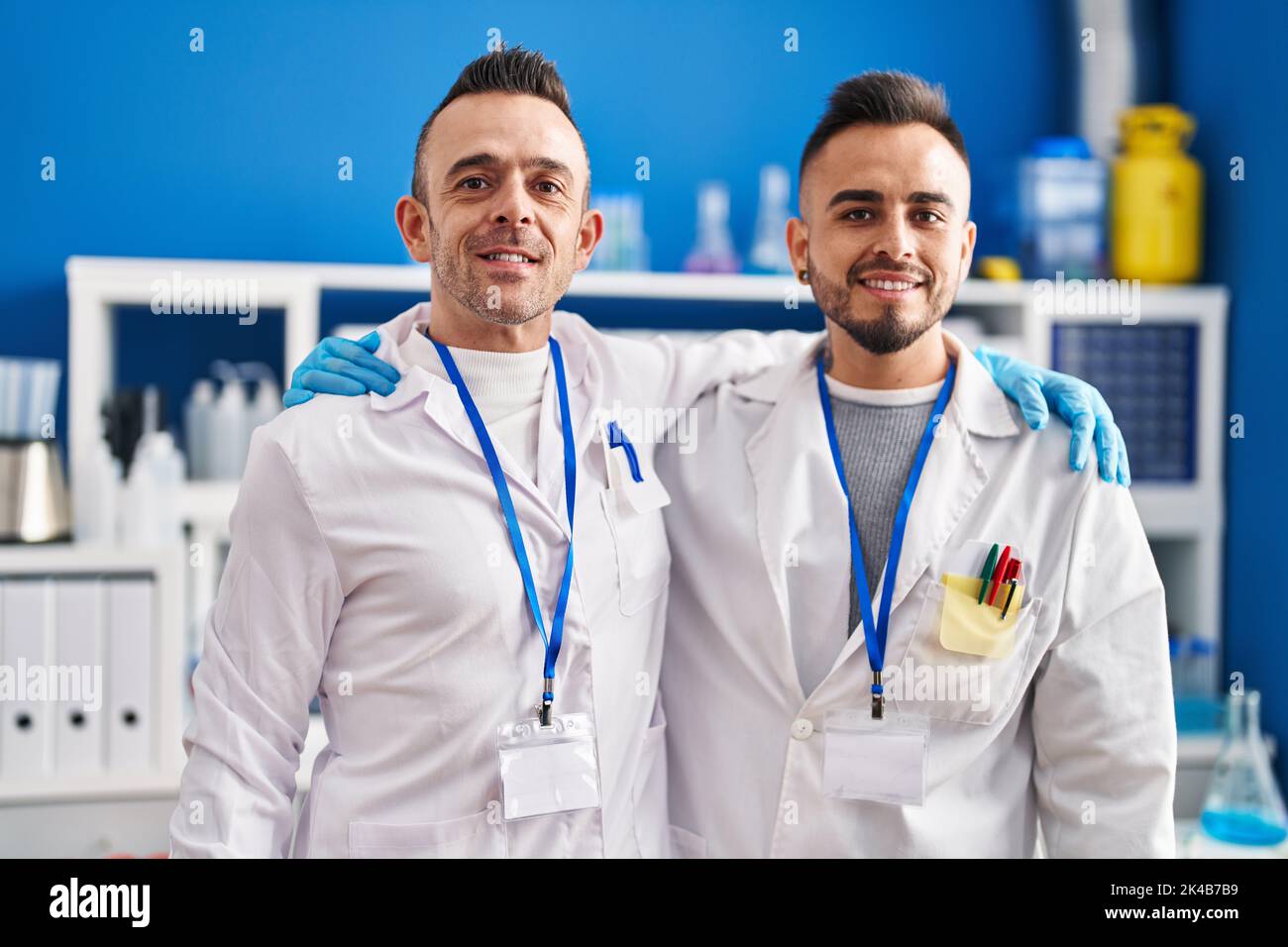 Two men scientists smiling confident hugging each other at laboratory ...