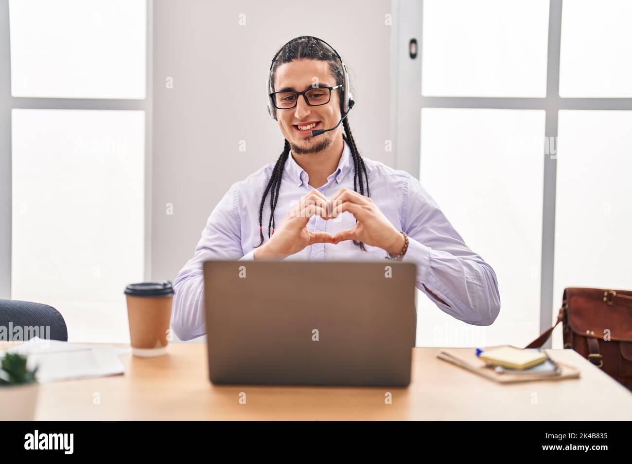 Hispanic man with long hair working using computer laptop smiling in ...