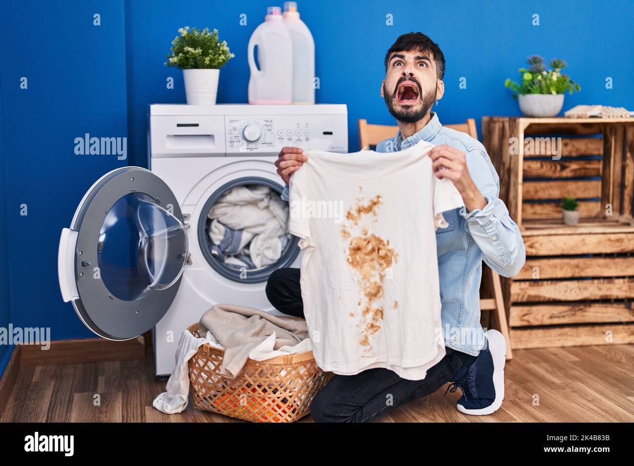 Young hispanic man with beard holding clean white t shirt and t shirt ...
