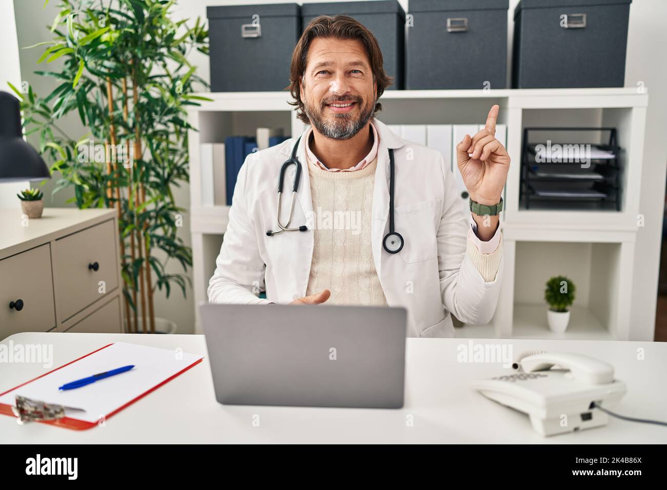 Handsome middle age doctor man working at the clinic with a big smile ...