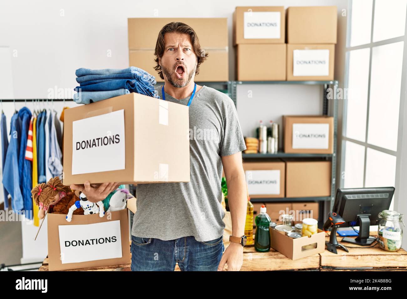 Handsome middle age man holding donations box for charity at volunteer ...