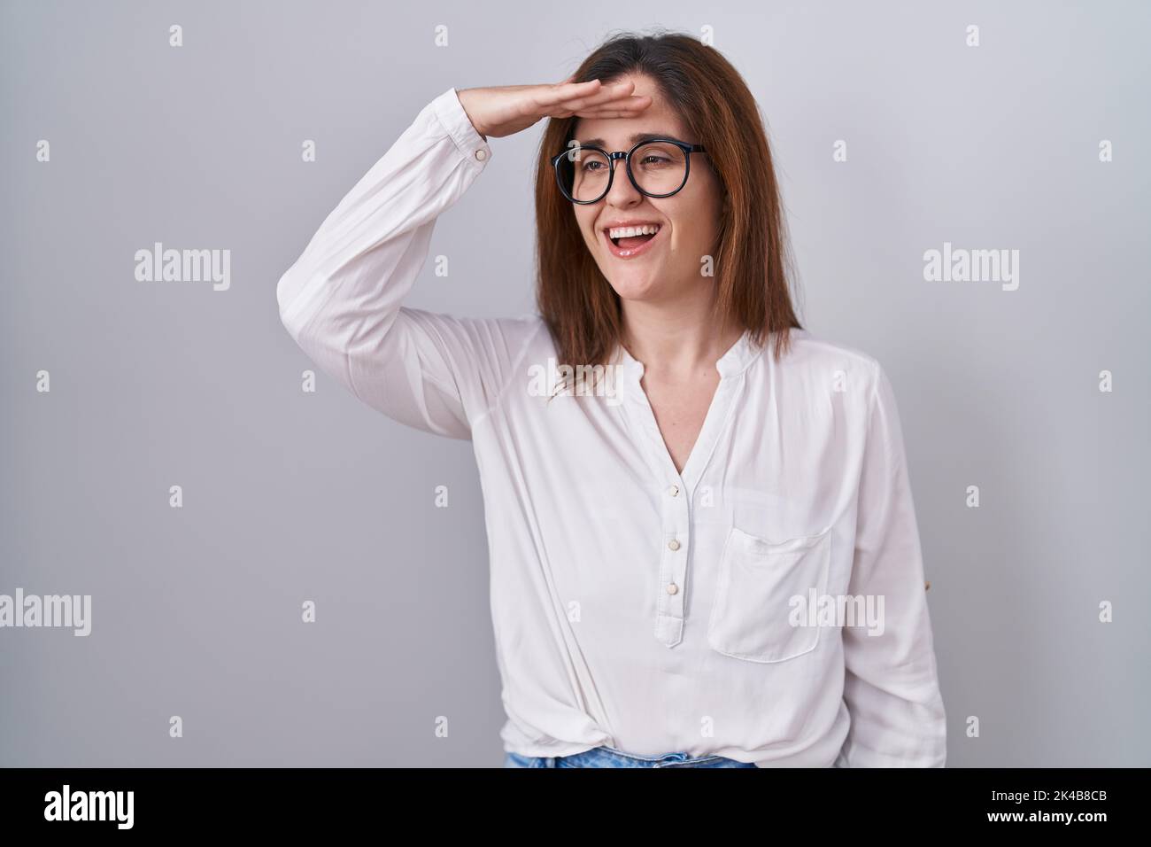 Brunette woman standing over white isolated background very happy and ...