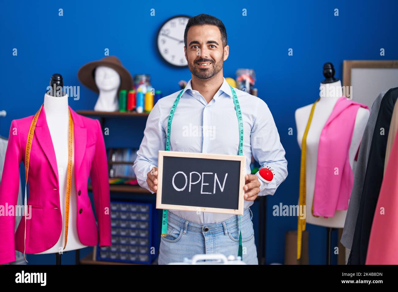 Hispanic man with beard working as dressmaker at atelier smiling with a ...