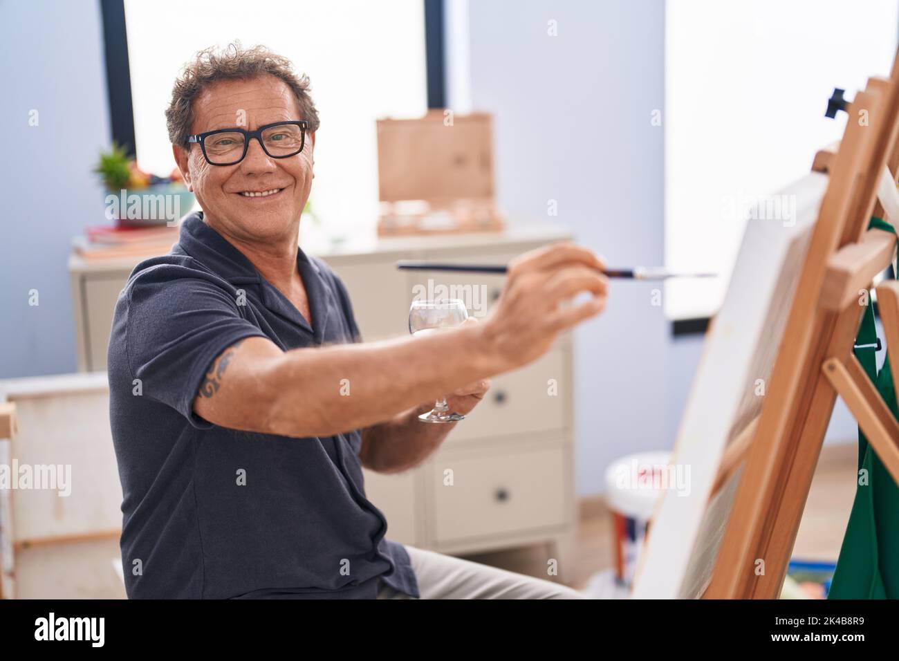 Middle age man artist drinking wine drawing at art studio Stock Photo ...