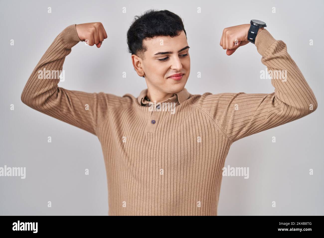 Non binary person standing over isolated background showing arms ...