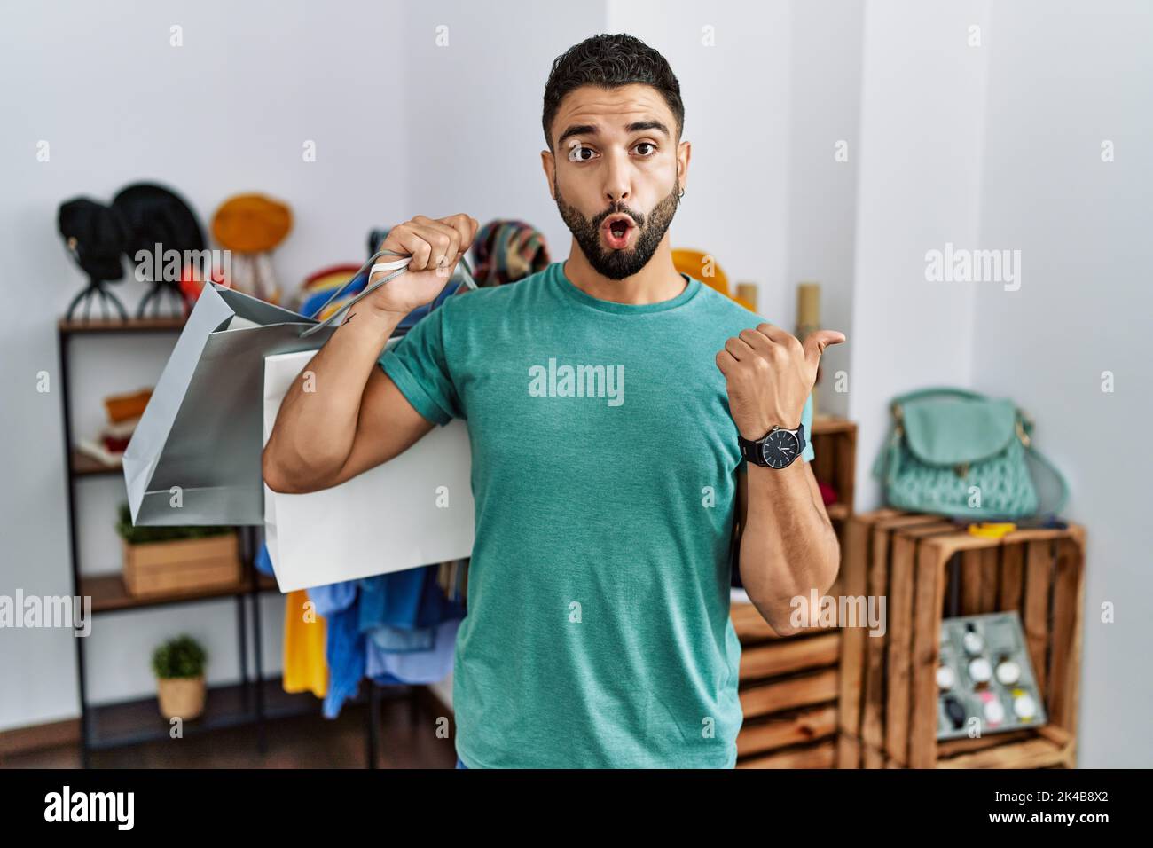 Young handsome man with beard holding shopping bags at retail shop ...