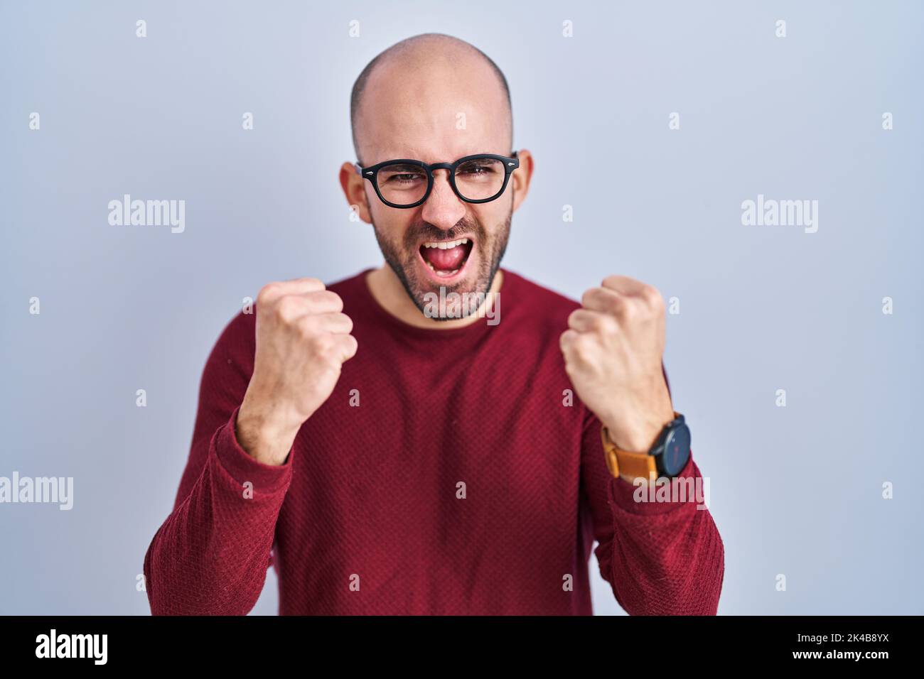 Young bald man with beard standing over white background wearing ...