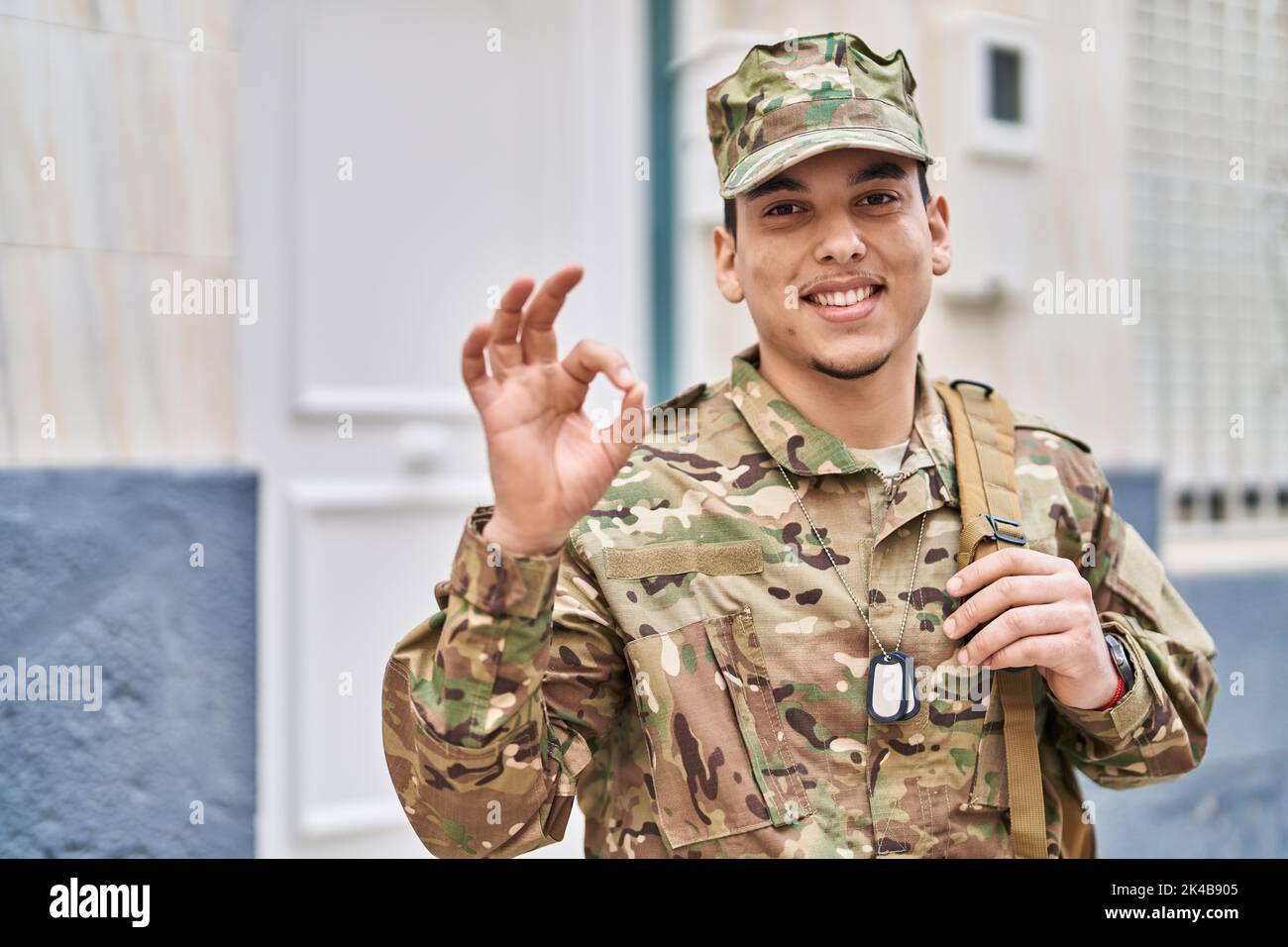 Young arab man wearing camouflage army uniform outdoors doing ok sign ...