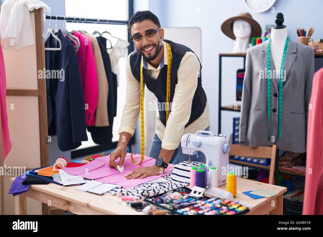 Young arab man tailor smiling confident make mark on cloth at clothing ...