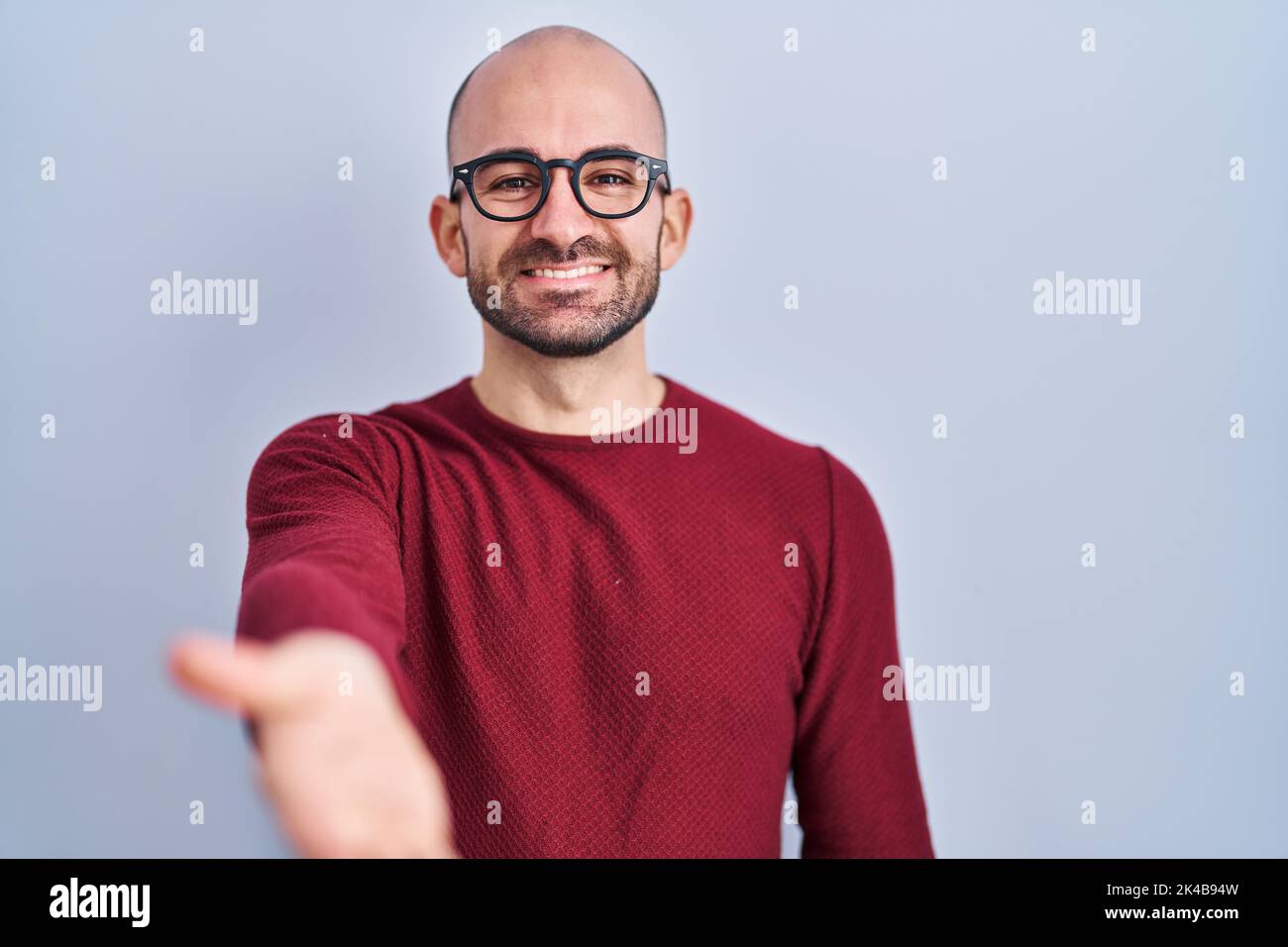 Young bald man with beard standing over white background wearing ...