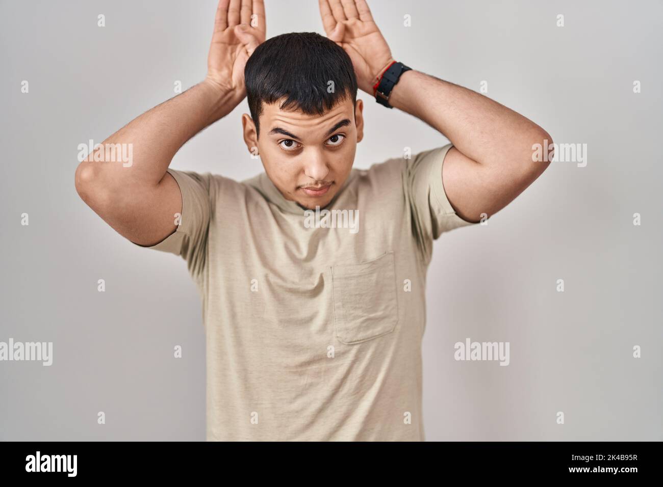 Young arab man wearing casual t shirt doing bunny ears gesture with ...