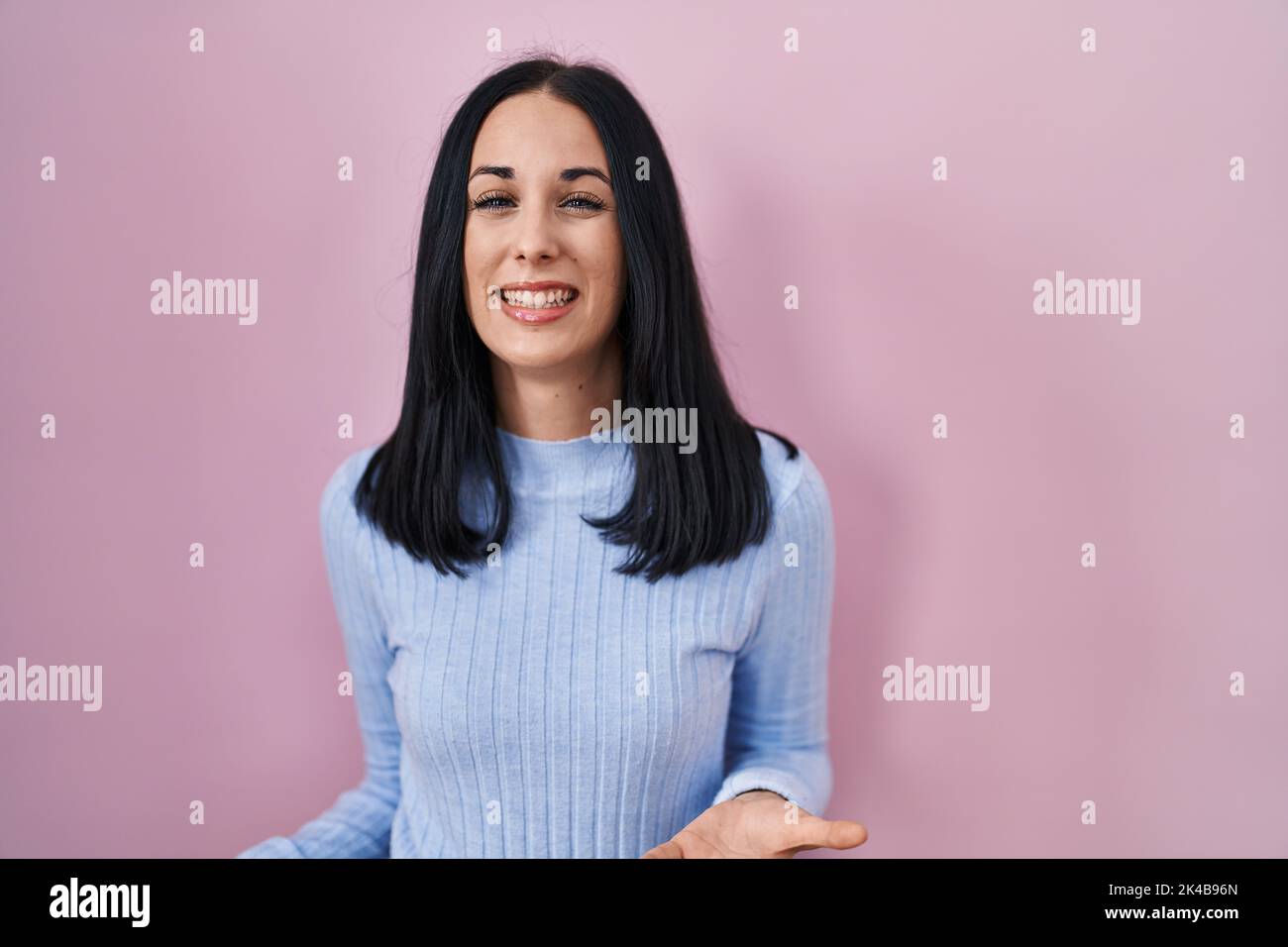 Hispanic woman standing over pink background smiling cheerful with open ...