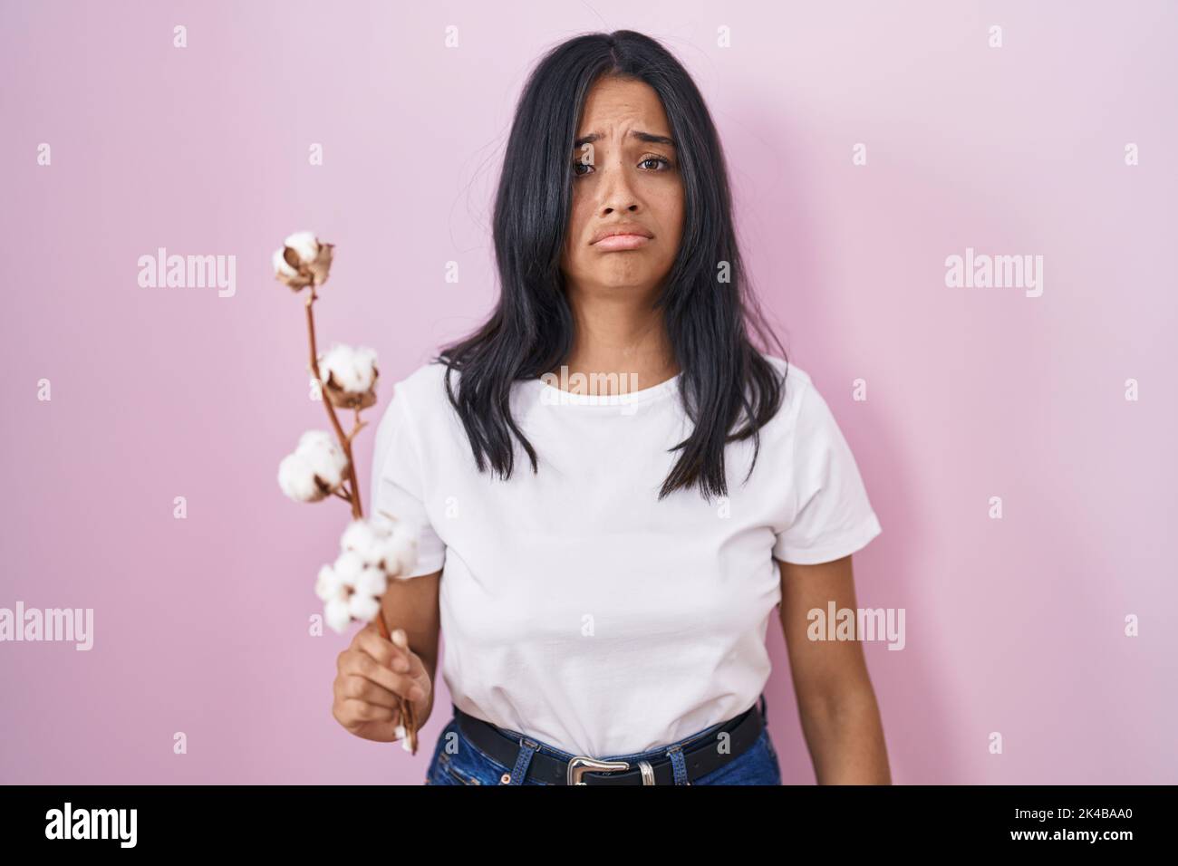 Brunette woman standing over pink background depressed and worry for ...