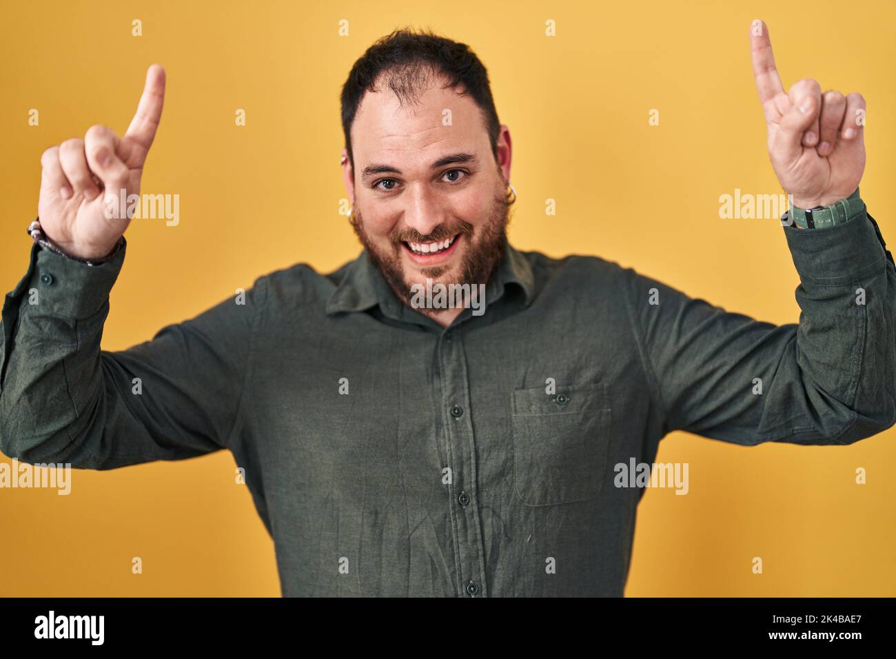 Plus size hispanic man with beard standing over yellow background ...