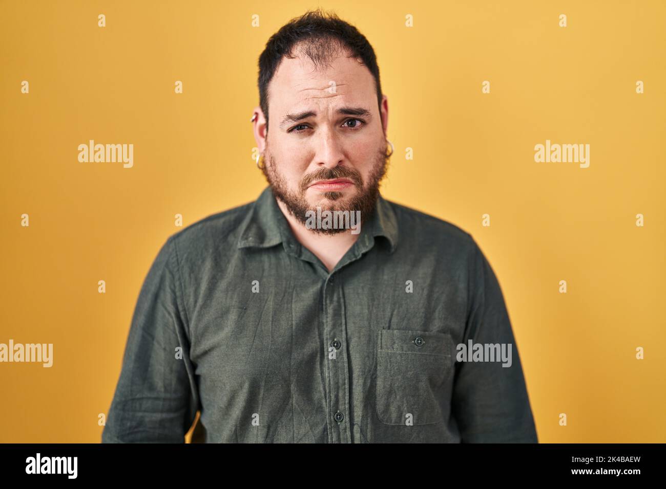 Plus size hispanic man with beard standing over yellow background ...