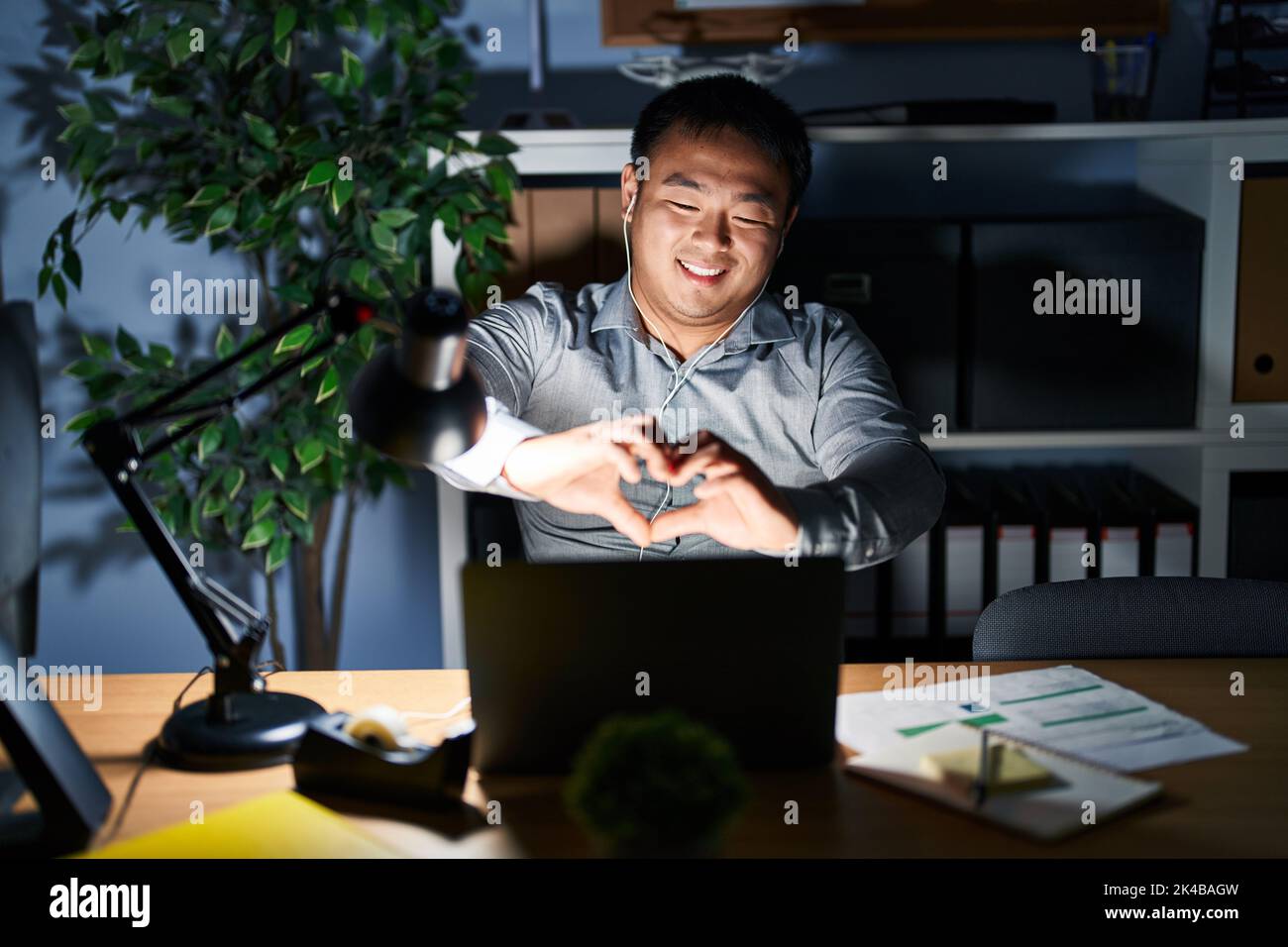 Young chinese man working using computer laptop at night smiling in ...