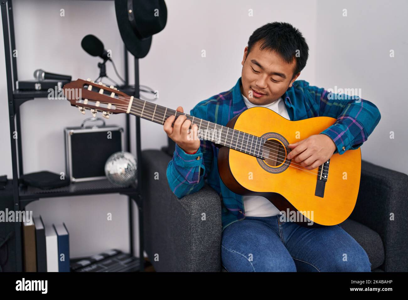 Young chinese man guitarist playing classical guitar at music studio ...