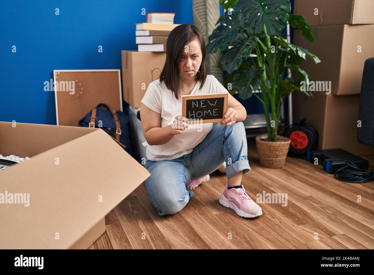 Hispanic girl with down syndrome sitting on the floor at new home ...
