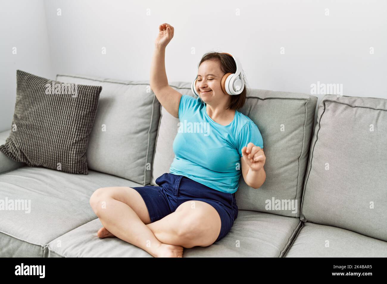 Brunette woman with down syndrome sitting on the sofa wearing ...