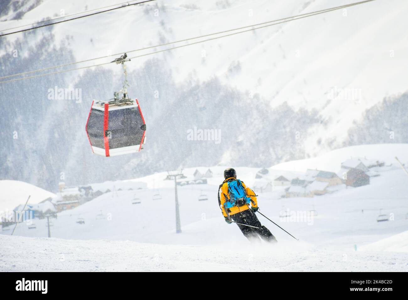 Male skier skiing downhill fast pass cabin lift in snowy conditions to ...