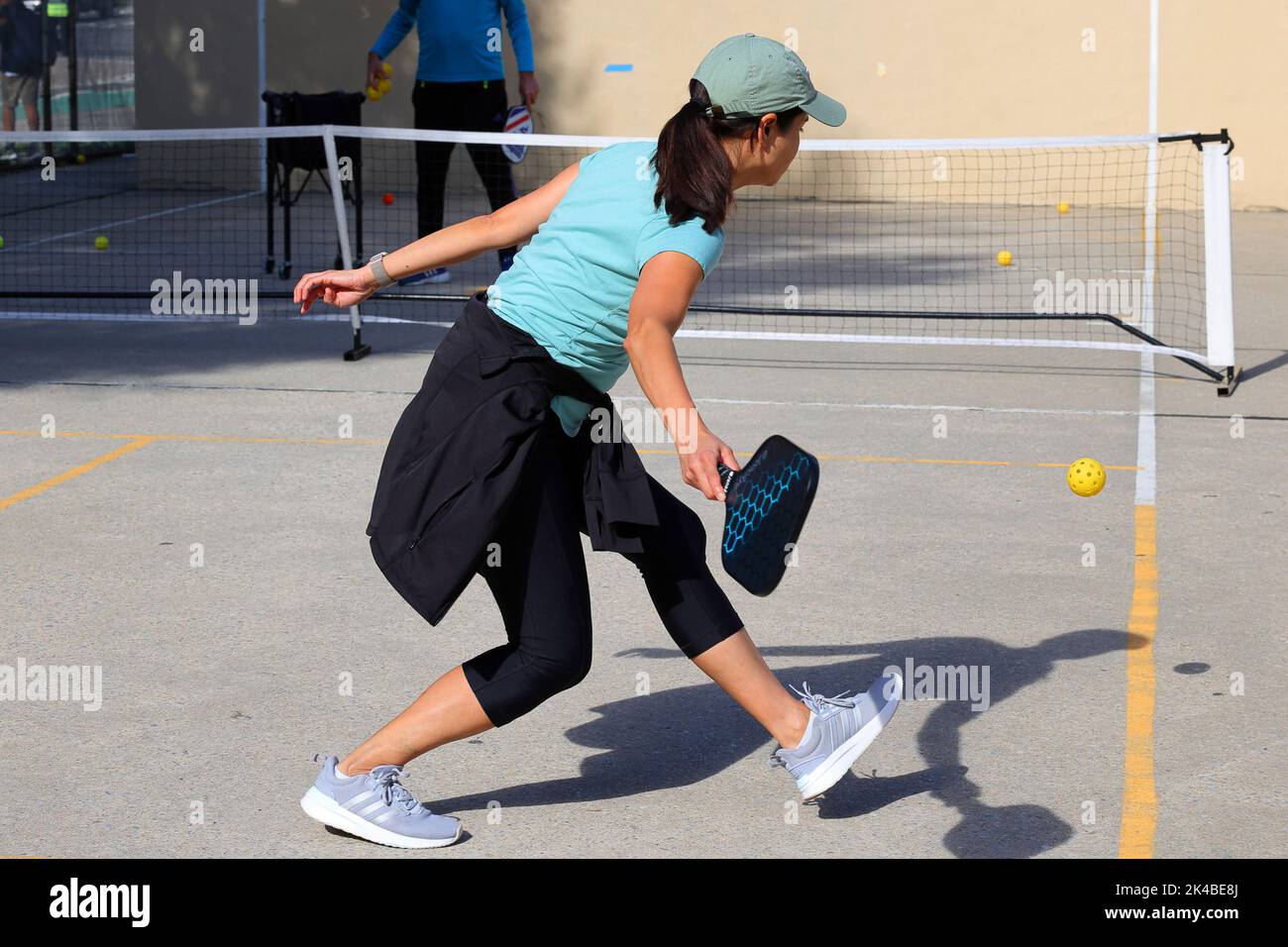 An Asian woman playing pickleball. Woman returns a pickleball serve, at ...