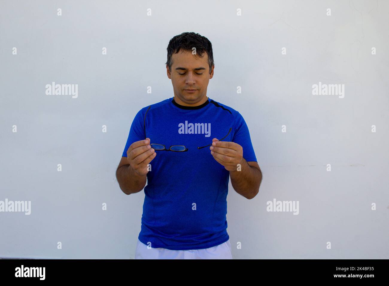 Image of a man holding a pair of broken eyeglasses. Breaking the temple ...