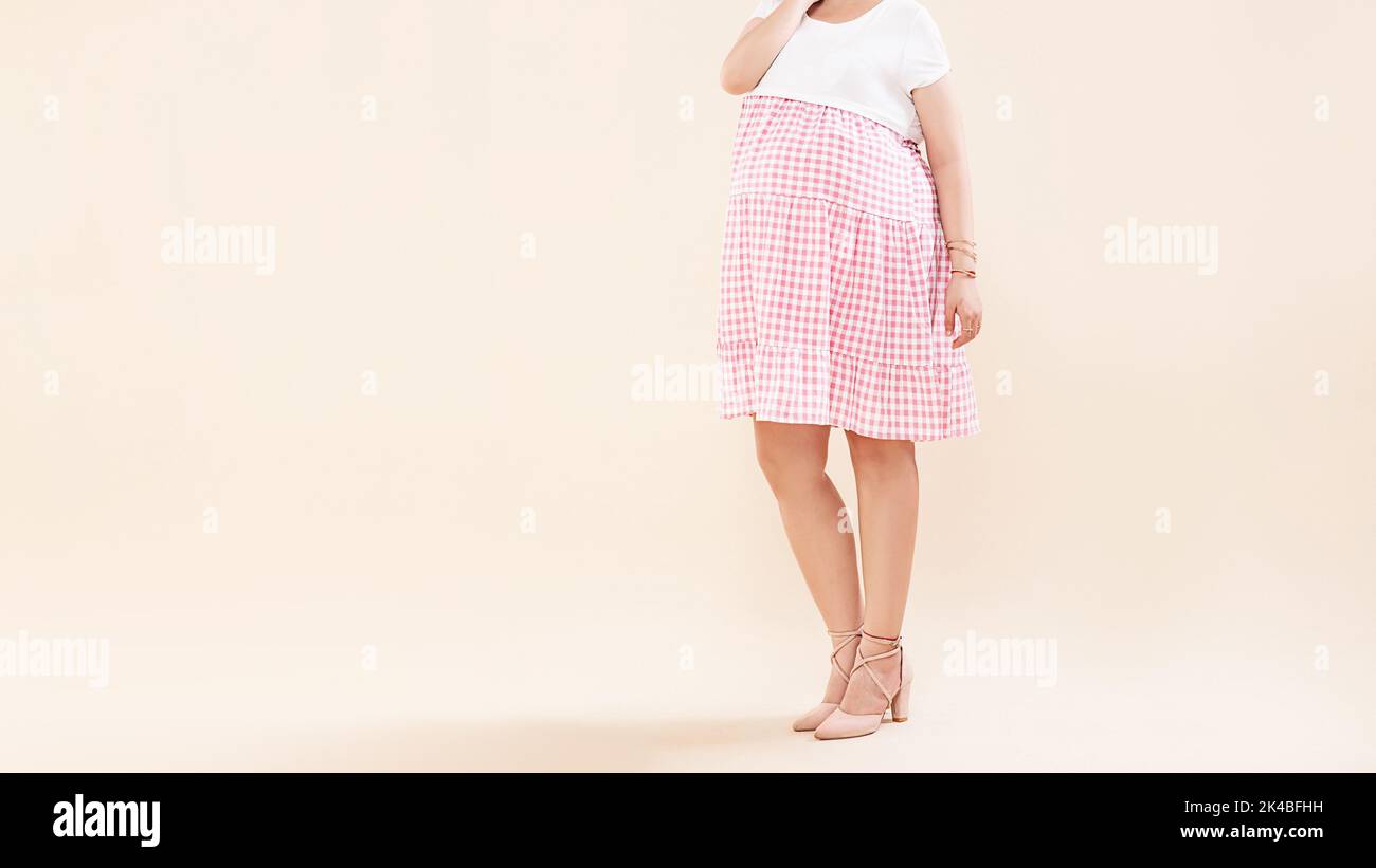 Beautiful pregnant woman standing in pink pastel caro dress with beige ...
