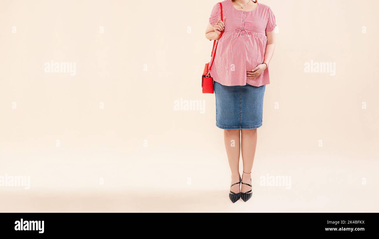 Beautiful pregnant woman standing in red fashion caro dress with black ...