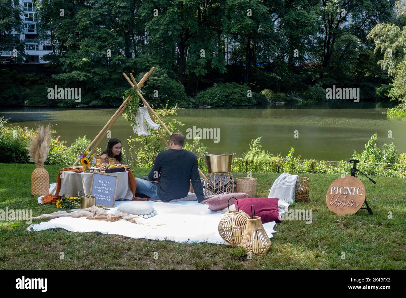 A couple enjoys a catered picnic at the pond in Central Park on a sunny ...